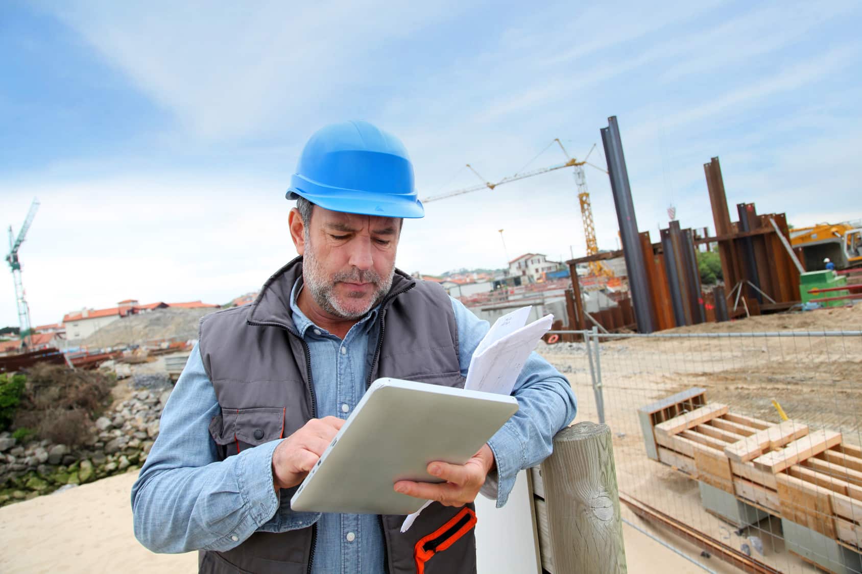 Construction manager controlling building site with plan – Construction Information Services (CIS)